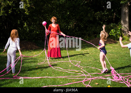Woman throwing a pink ball of string to children during a drama ...