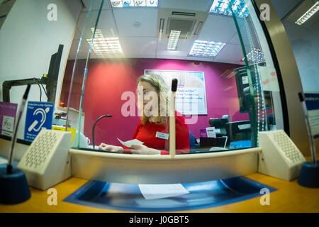 a woman bank teller working behind the counter at a branch of HSBC high ...