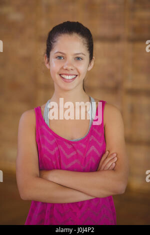 Portrait of a happy school girl standing in class room with school bag ...