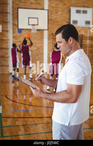 Basketball coach writing on clipboard Stock Photo - Alamy