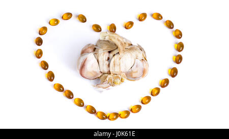 Organic garlic and garlic capsules in heart shape in front of white ...