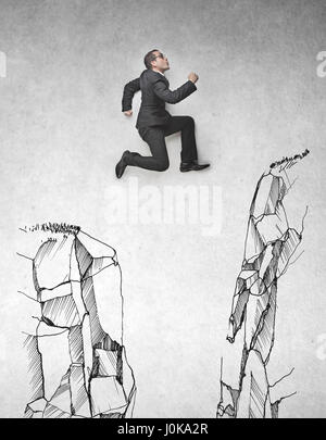 Businessman jumping over the cliff Stock Photo - Alamy