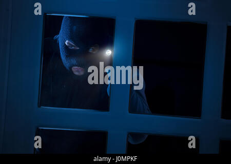 Burglar with looking through the window at night Stock Photo - Alamy