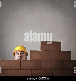 Construction worker hiding behind a wall Stock Photo - Alamy