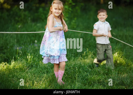 Happy group of kids playing tug of war in a park Stock Photo - Alamy