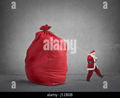 Santa Claus pulling huge bag of gifts isolated on white with copy space ...