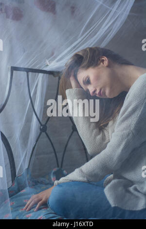 Sad woman sat on bed Stock Photo - Alamy