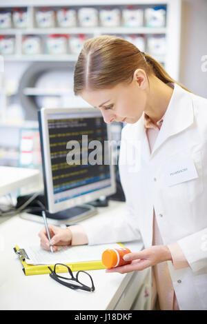 Young woman pharmacist talking on telephone reading prescription at ...