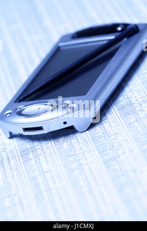 A shot of a PDA on top of financial chart in blue tone Stock Photo - Alamy