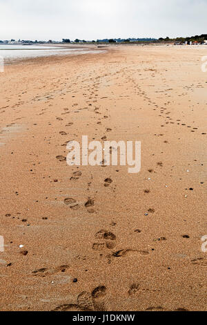 Empty sand with footprints, in front of beach houses, under blue sky ...