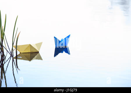 two multicolored paper boats floating on a stream outdoor on autumn day ...