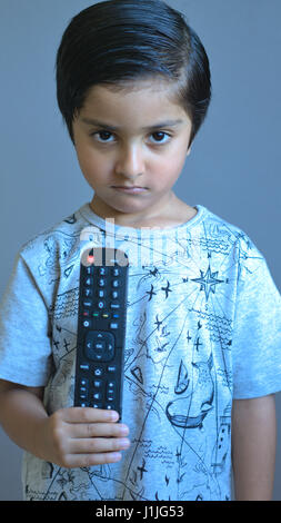 Kid holding TV remote controller. Boy without parental control watching ...