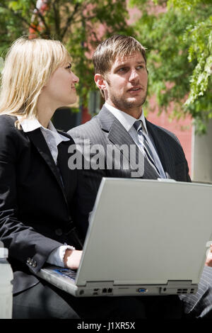 Business professionals having an outdoor discussion with notebooks ...