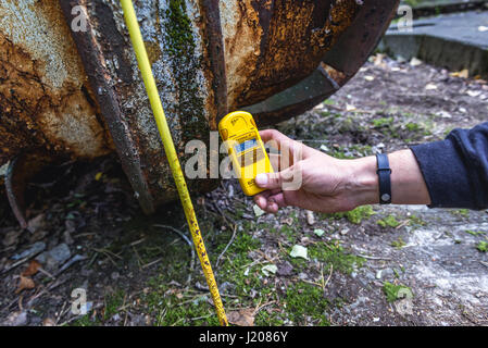 Tourist examine irradiated scrap bucket in Pripyat city of Chernobyl ...