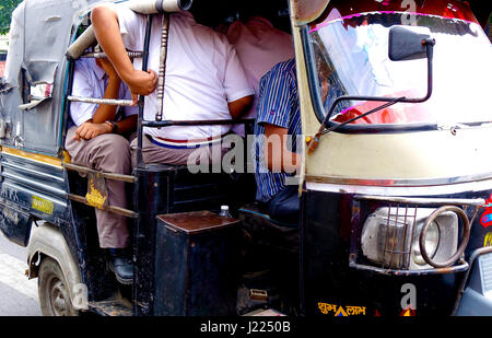 An overloaded three-wheeler auto rickshaw with local people travelling ...