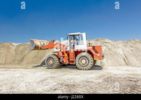 Red loader with wheels at earth moving works, he is pushing sand on ...