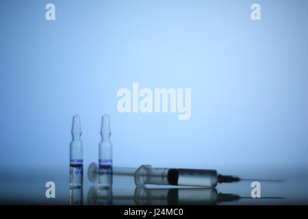 Ampoules with a medicine and a syringe on a light background ...