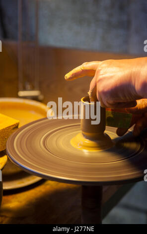 Potter making and molding a ceramic vessel with both hands in his ...