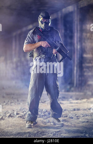 Man player shooting with a paintball gun hiding behind wooden shelter ...