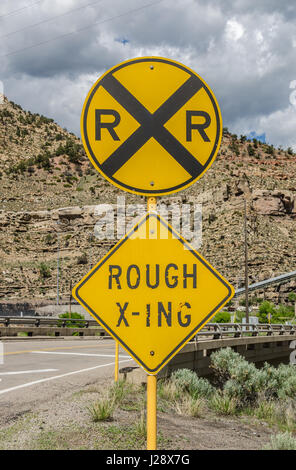 Yellow railroad crossing warning sign on rural road with trees and ...