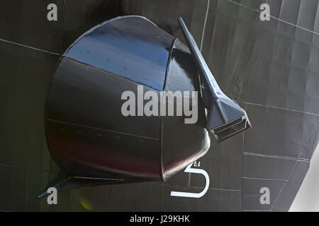 A close - up view of a ship's anchor housed in it's hawse pipe recessed ...