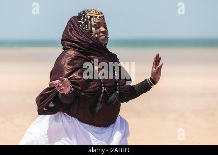 Africa, Western Sahara, Dakhla. Woman in traditional dress playing an ...