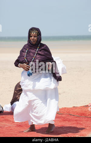 Africa, Western Sahara, Dakhla. Woman in traditional dress playing an ...