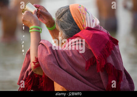 Woman carrying out puja (hindu devotion) by the river Ganges at Kumh ...