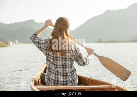 Back of female traveler paddling canoe Stock Photo - Alamy