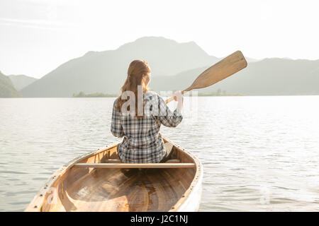 Back of female traveler paddling canoe Stock Photo - Alamy
