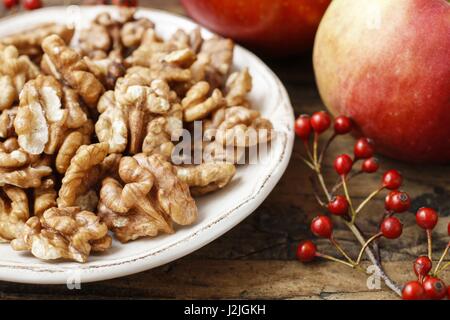 Bowl of walnuts and red apples on wooden table. Healthy snacks Stock ...