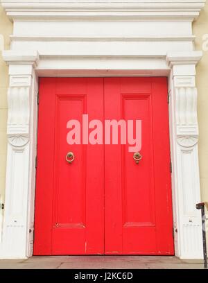 Bright red double doors with a white stone arch and keystone on a ...