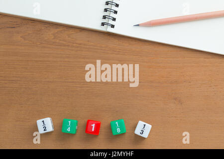 Color fraction dices, blank white notebook on wooden desk, with ...