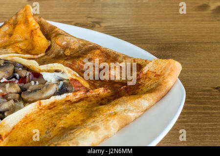 Delicious crepe with mushroom served on a white plate on a wooden table ...
