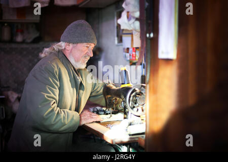 A senior adult man sewing a piece of cloth on a sewing machine Stock ...