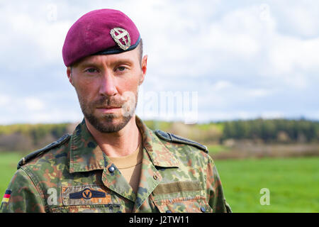 german soldier with a beret stands on a field background Stock Photo ...