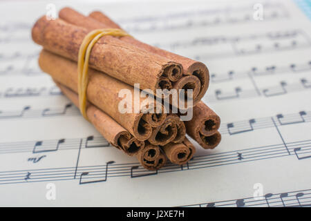 Bundles of Cinnamon sticks placed on a paper with musical notes Stock ...