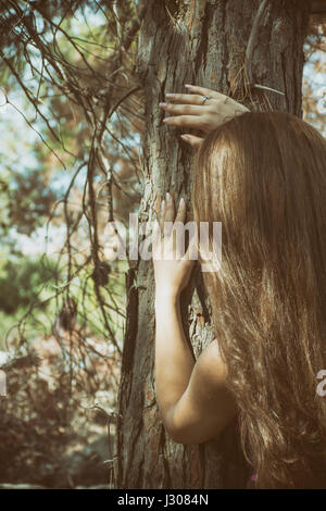 Muslim woman hiding behind a tree Stock Photo - Alamy
