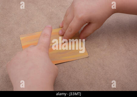 Hand holding painted note paper on brown background Stock Photo - Alamy