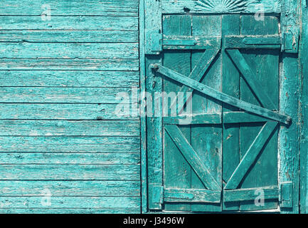 Turquoise blue wooden shutter slats with a yellow frame on a window of ...