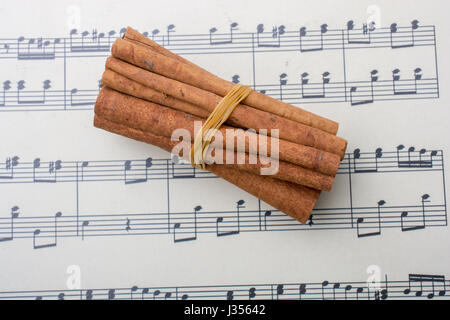 Bundles of Cinnamon sticks placed on a paper with musical notes Stock ...