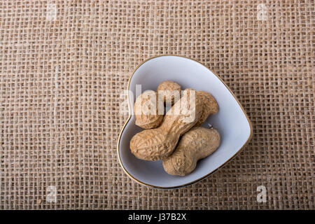 Peanuts in a heart shaped plate on canvas background Stock Photo - Alamy