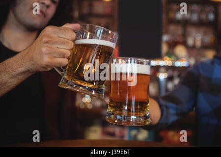 Young men toasting with beer mugs in a beer hall at Oktoberfest in ...