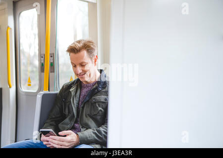 Man using smart phone while sitting on window seat at home Stock Photo ...