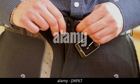 Man in blue shirt buckling undoes the belt on his pants Stock Photo - Alamy