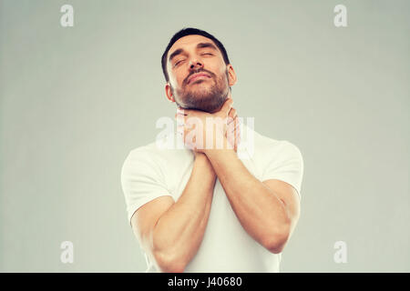 young man choking himself over gray background Stock Photo - Alamy