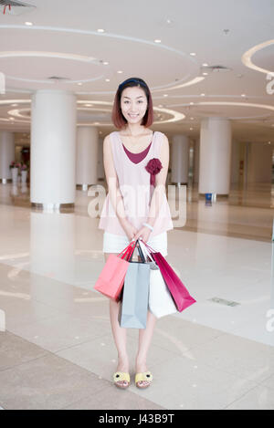 Beautiful young Asian woman with bag full of fresh products on yellow ...
