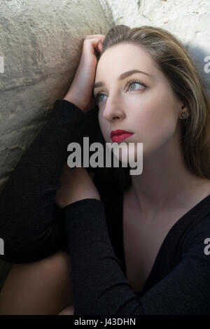 Sad young woman hand on face looking down Stock Photo - Alamy