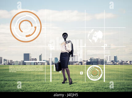 Camera headed woman standing on green grass against modern cityscape ...