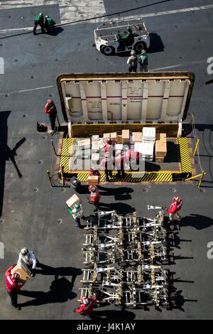 Sailors load cargo onto a weapons elevator in the hangar bay of USS ...